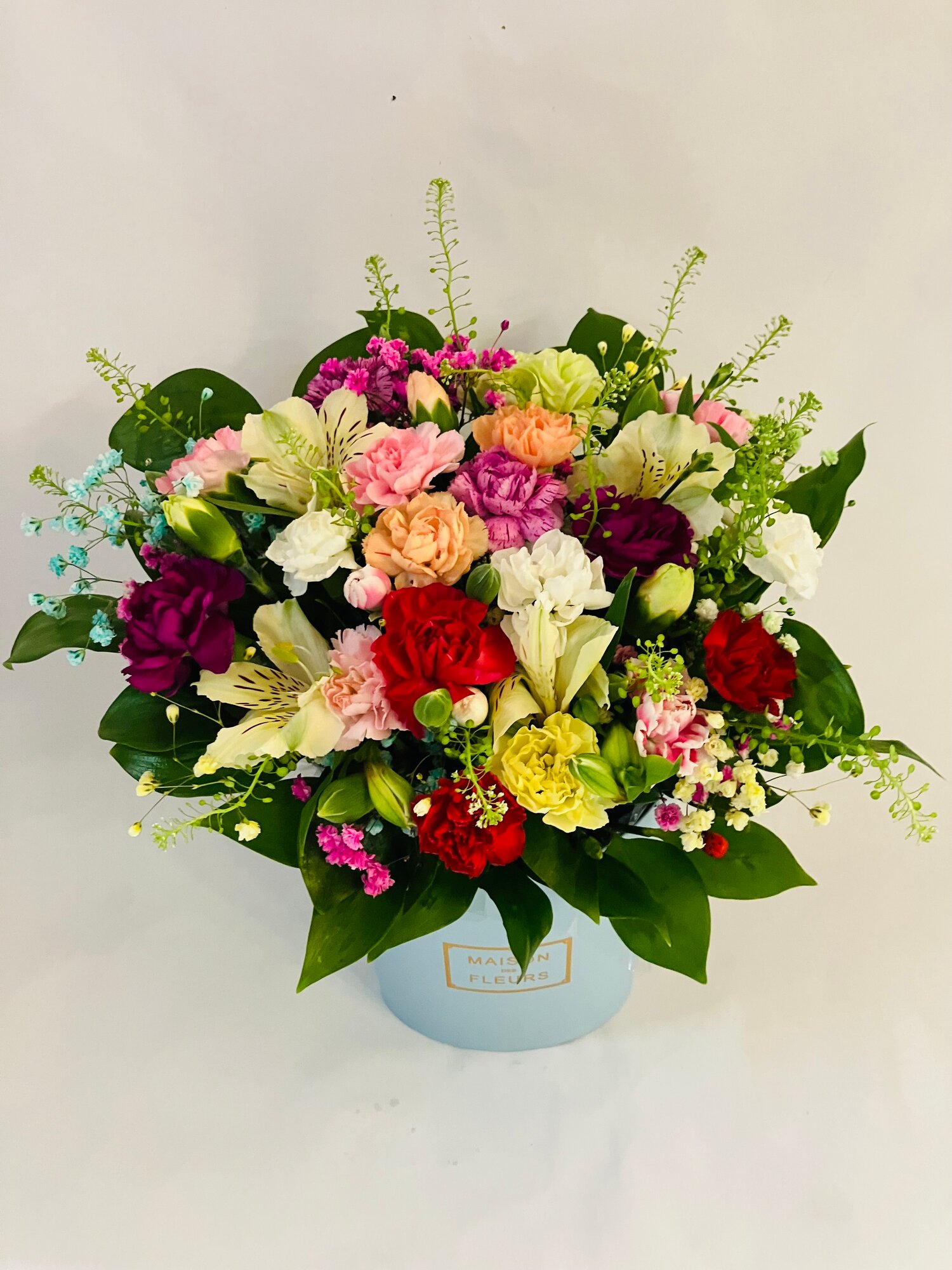 Букет Композиция из кустовых гвоздик, гринбелла и белой альстромерии в серо-голубой коробке