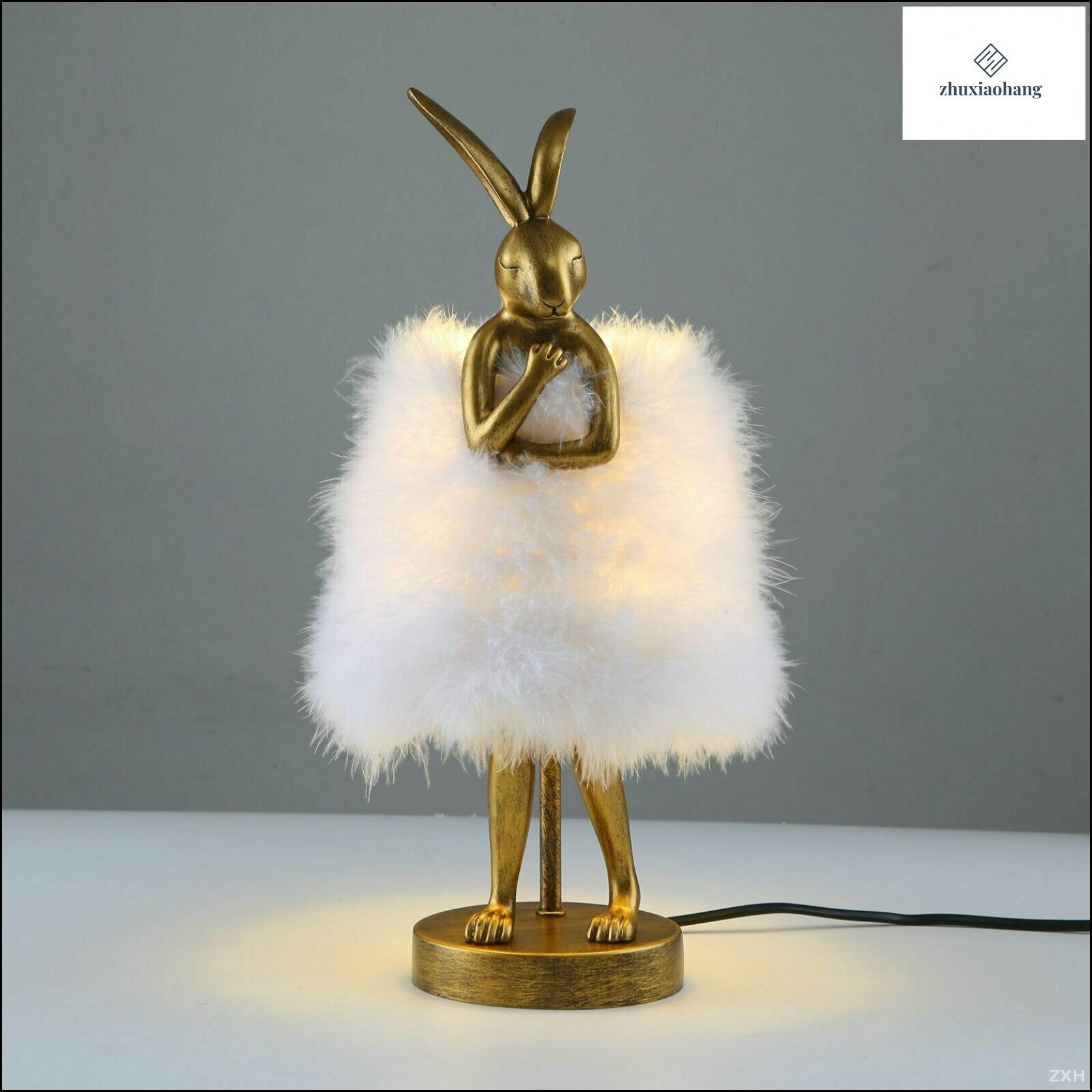 Эксклюзивная настольная лампа со светодиодным источником света, декорированная фигуркой кролика из золотистой смолы, обеспечивает бережную защиту зрения и используется для организации прикроватного и рабочего освещения в домашнем или офисном интерьере
