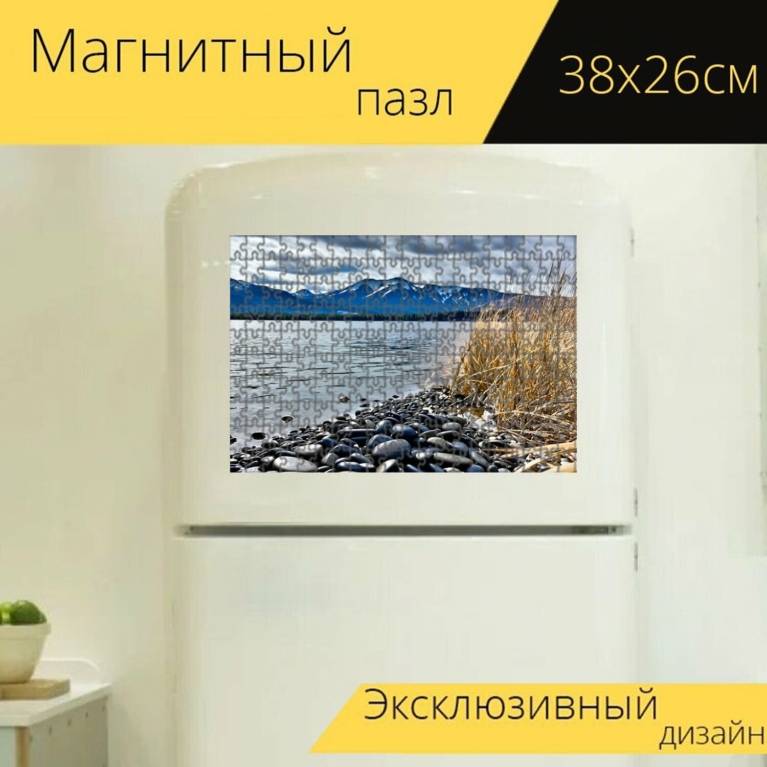 Магнитный пазл "Темная галька на берегу озера, окруженная сухими травами, ведущая к спокойной воде, вдалеке величественные горы под облачным небом." для интерьера, 38х26 см.