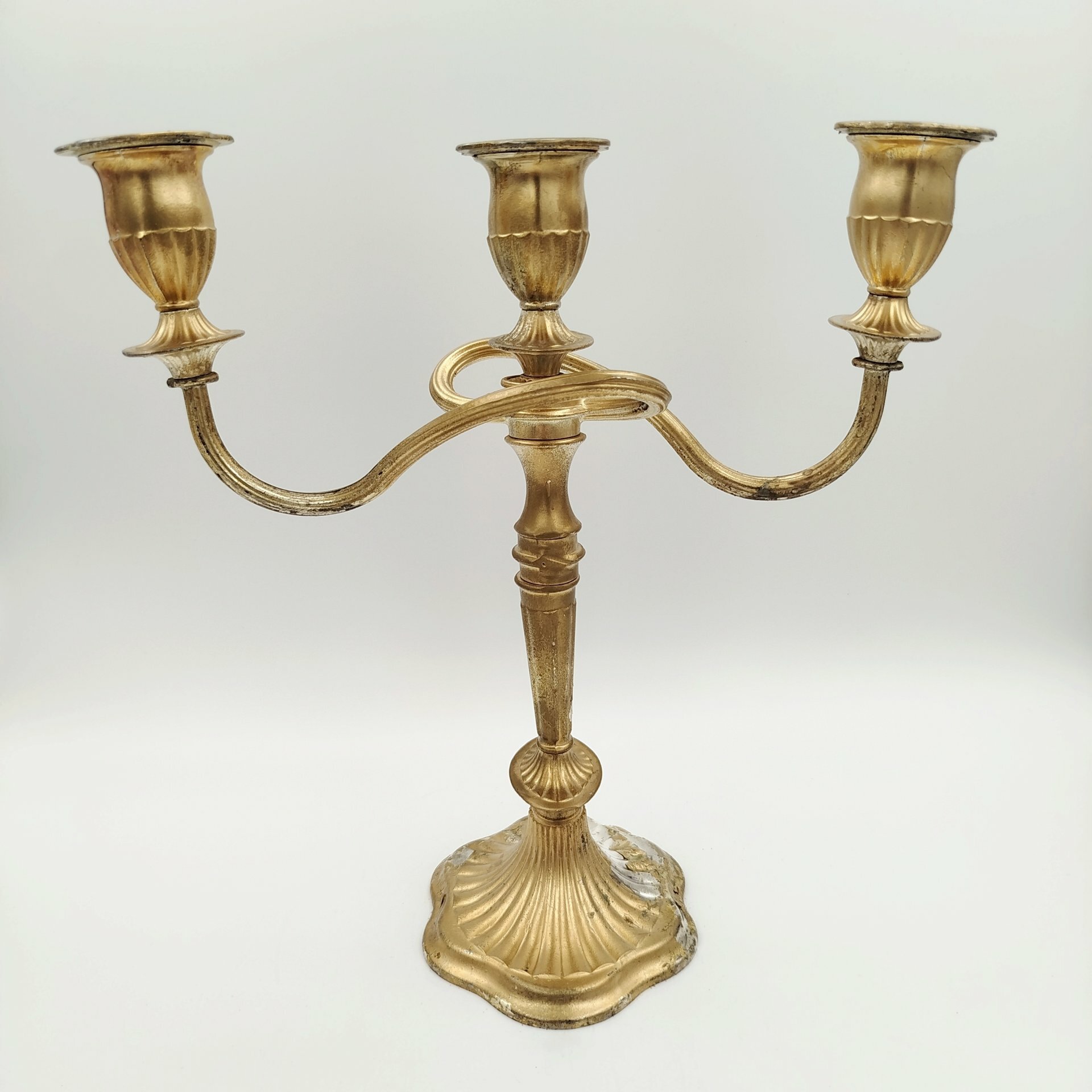 Канделябр золотистого цвета с витиеватыми рожками, рассчитанный на три свечи