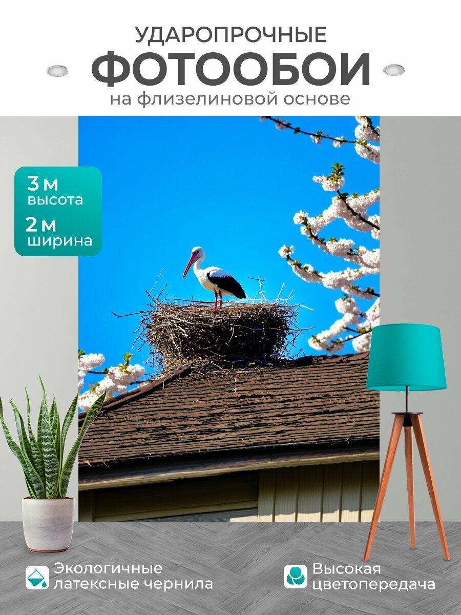 Фотообои моющиеся ударопрочные "Аист в гнезде на крыше старого дома, вокруг цветущие деревья и яркое голубое небо" 200x300 см. флизелиновые на стену