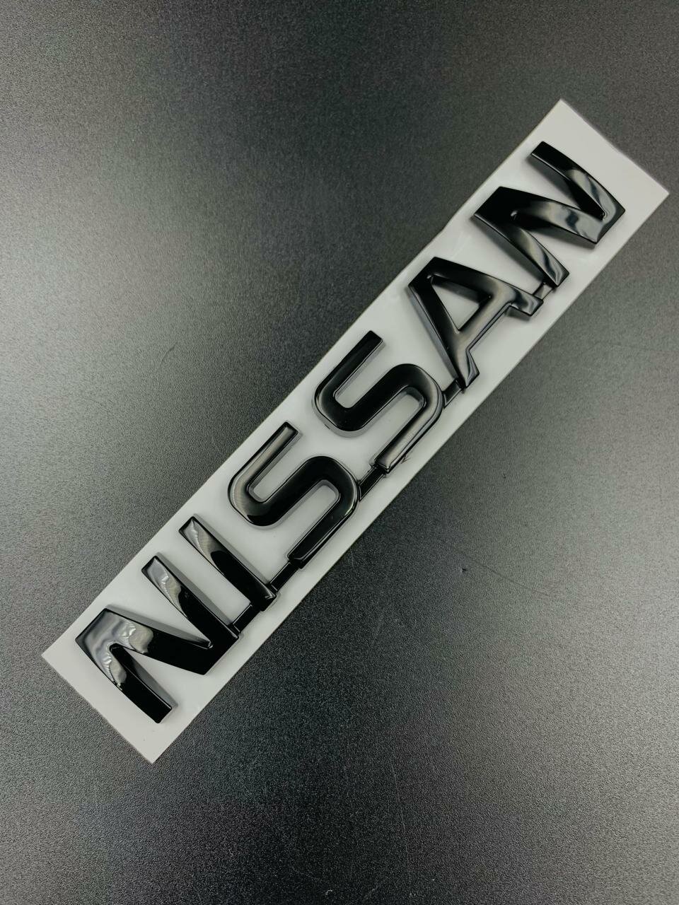 Значок надпись Ниссан 123мм. Эмблема шильдик на крышку багажника Nissan (черный глянец)
