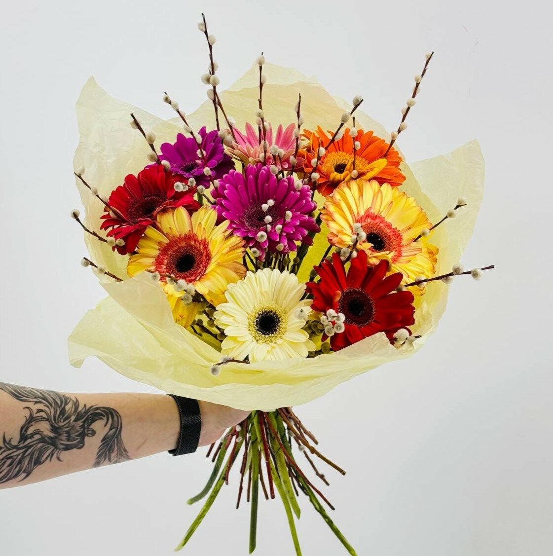 Пышный букет разноцветных гербер с веточками живой вербы. Герберы в дизайнерской упаковке. Букет на Пасху