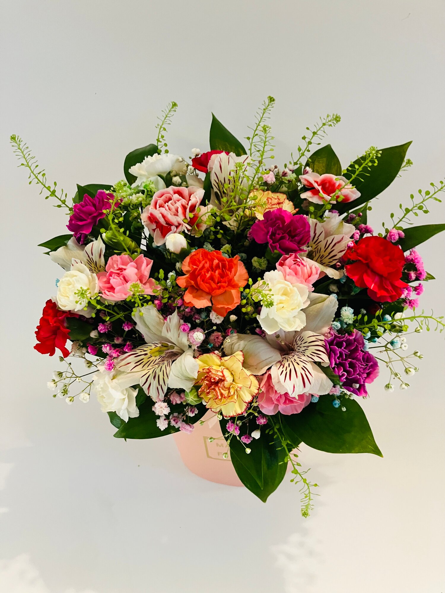 Букет композиция из кустовых гвоздик микс, с белой альстромерией, в розовой коробке Мейсон