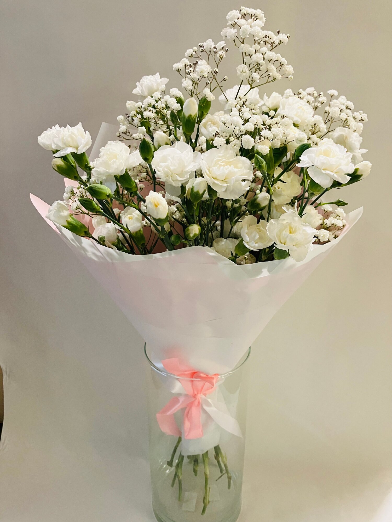 Букет из 11 белых, свежих, кустовых гвоздик с гипсофилой, в дизайнерской упаковке, атласный бант.