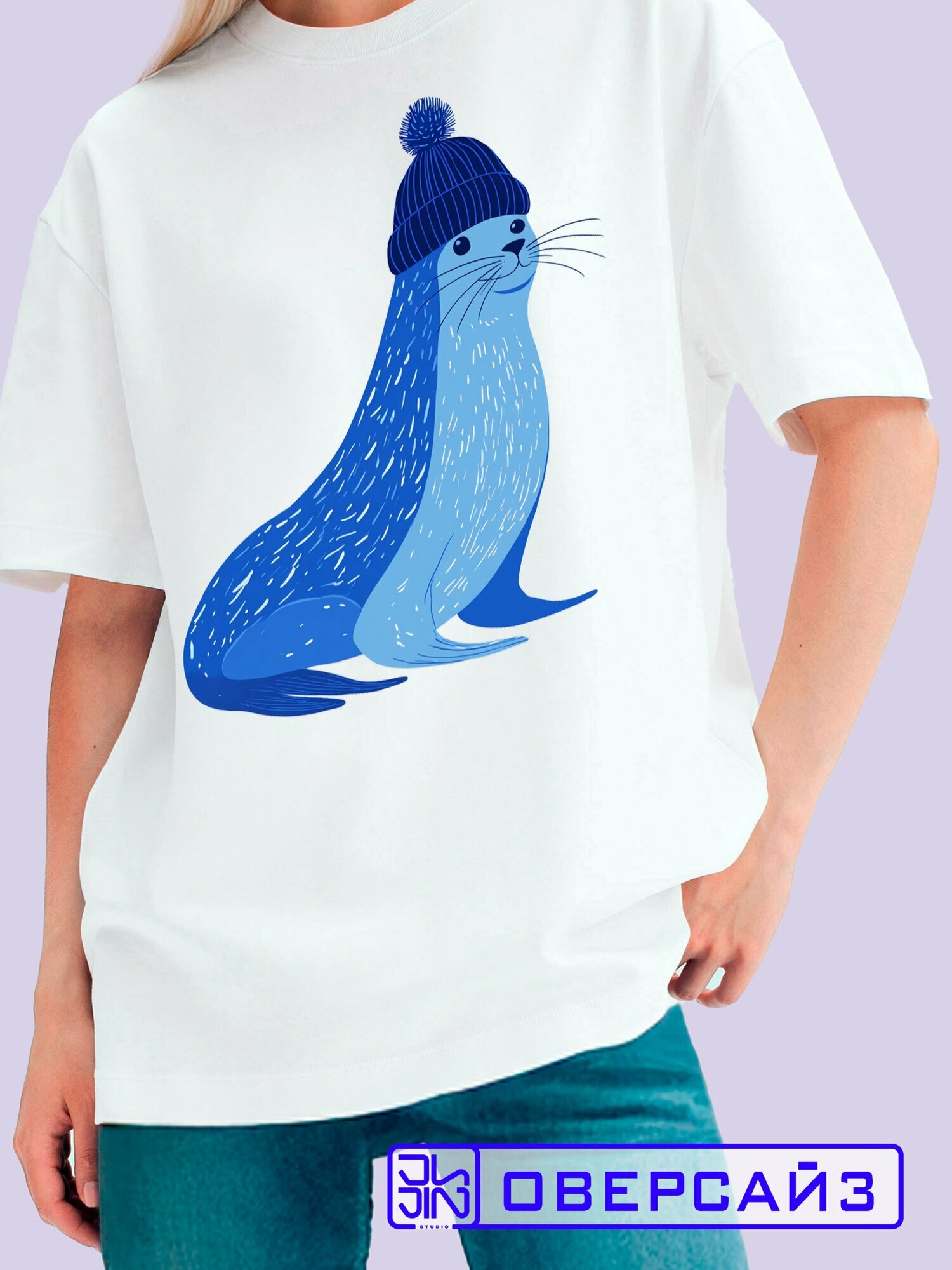 Футболка оверсайз женская с принтом Смешной веселый тюлень в темно синей, теплой шапке и синем образе с животными, белый хлопковый трикотаж с прикольным рисунком на груди