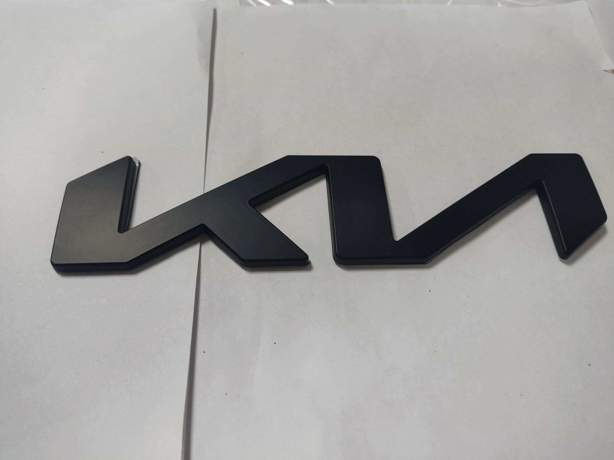 Эмблема (шильдик) Kia, металл, чёрный, матовая поверхность, самоклеящаяся