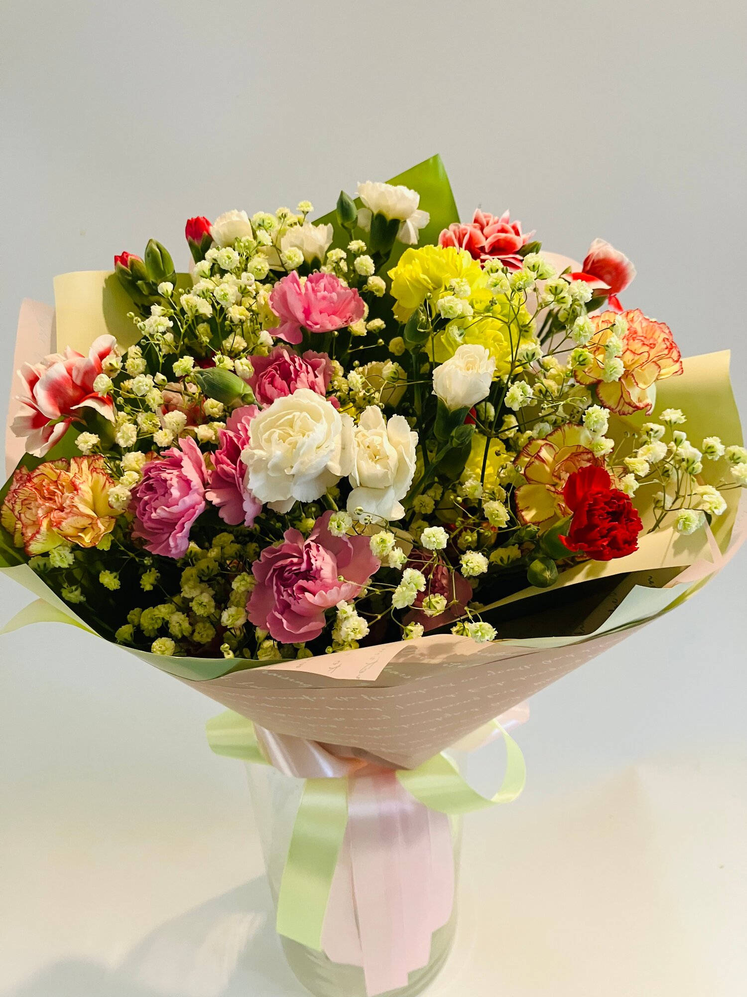 Букет из 13 свежих, кустовых гвоздик микс, с салатовой гипсофилой, дизайнерская упаковка, атласный бант.