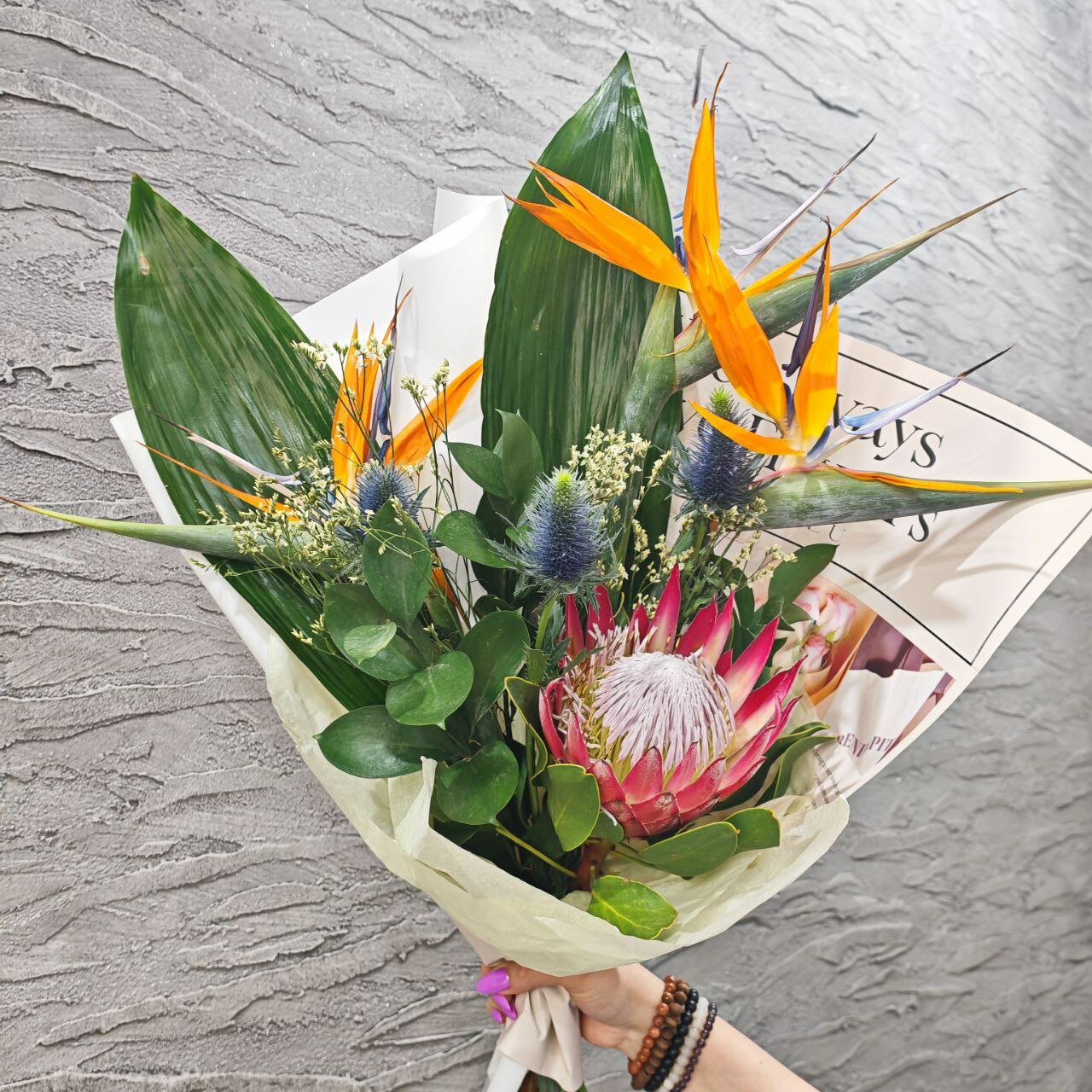 Дизайнерский букет из цветов протея, стрелиция, эрингиум, лимониум с зеленью аспидистра, рускус