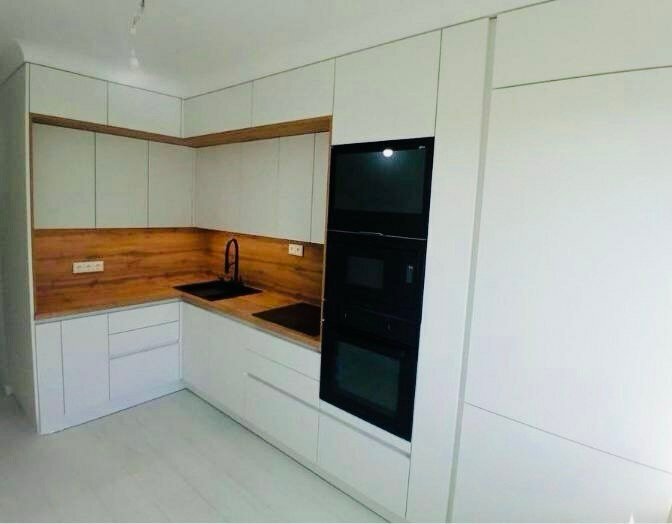 Белая акриловая кухня без ручек — профиль Gola, чёрные акценты и тёплое дерево