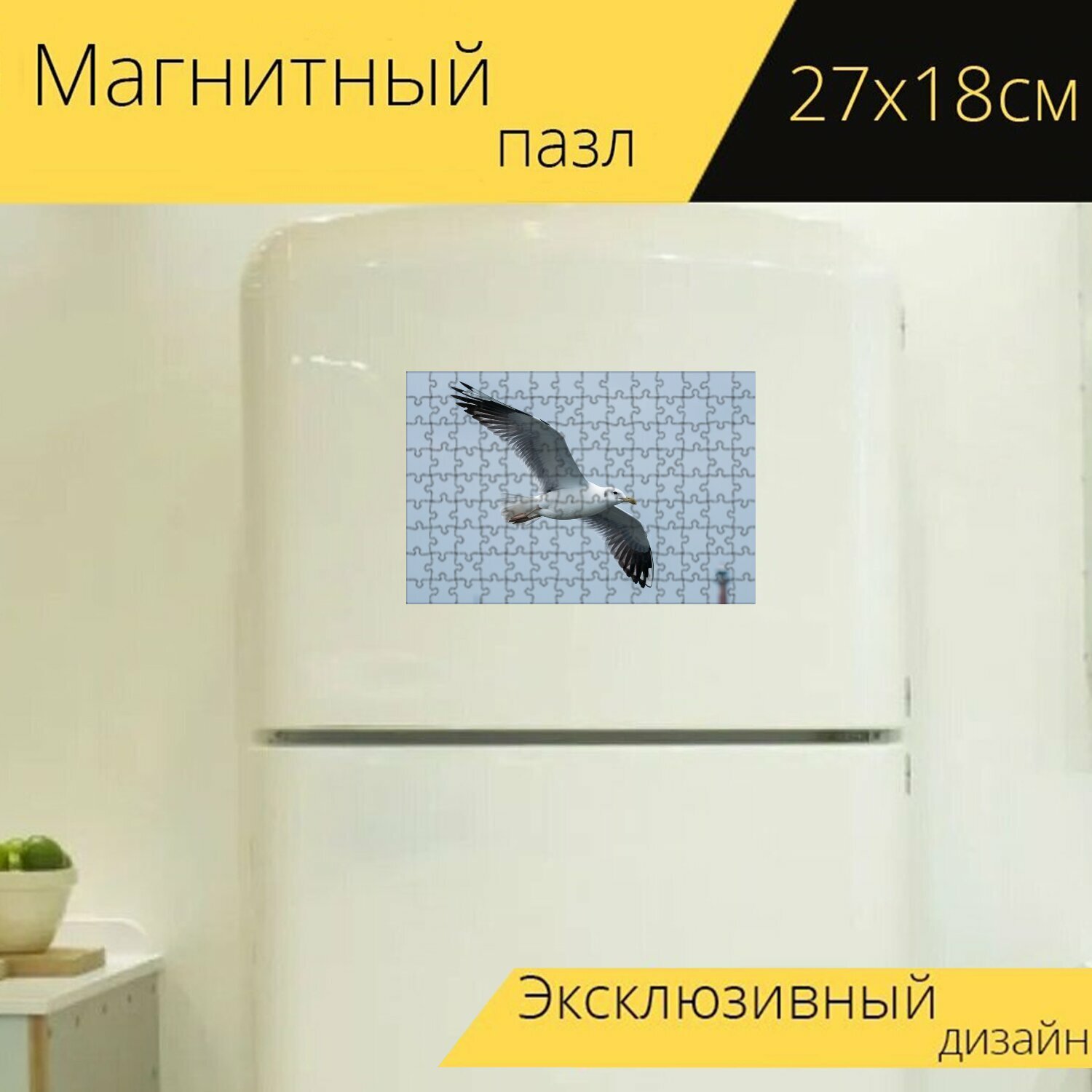 Магнитный пазл "Чайка в полёте над морем. Парящая морская птица с расправленными крыльями на фоне холодного неба и размытого портового берега." на холодильник 27 x 18 см.
