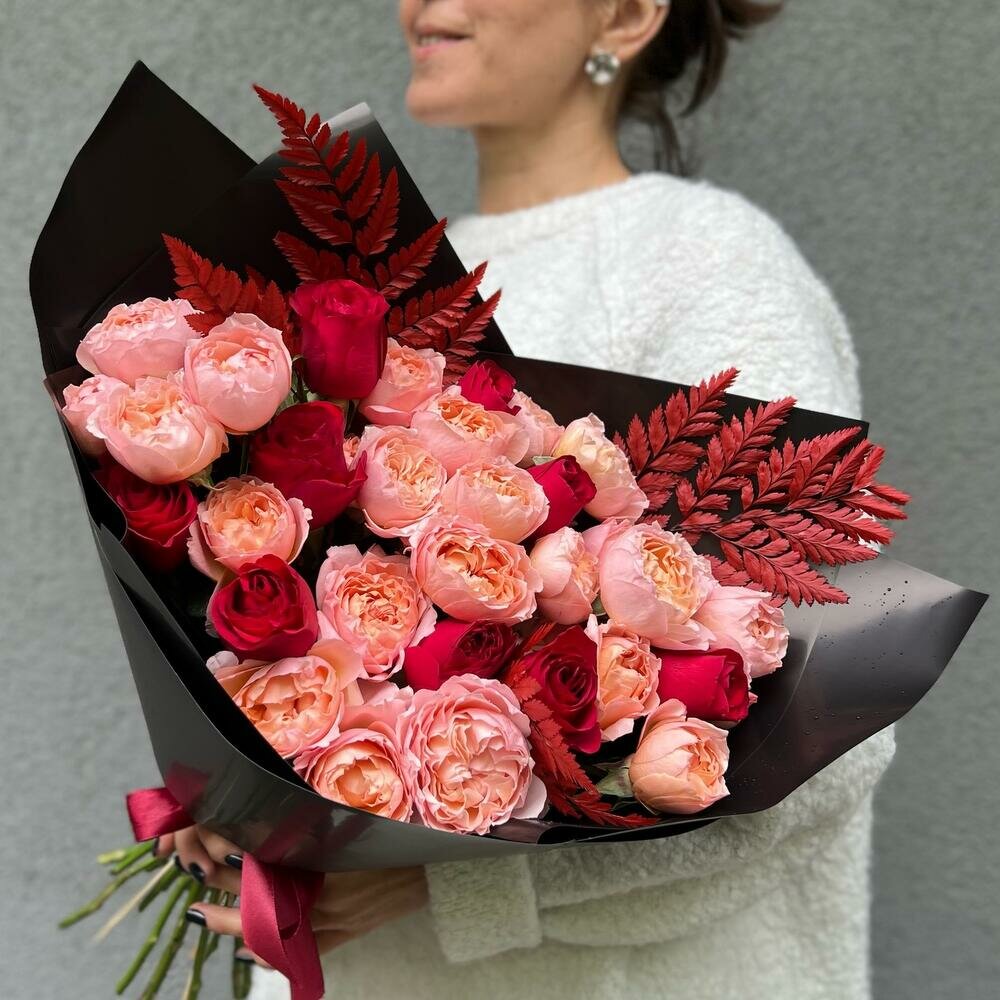 Букет из кустовых пионовидных роз Джульетта, красных роз и стабилизированного папоротника в черной упаковке
