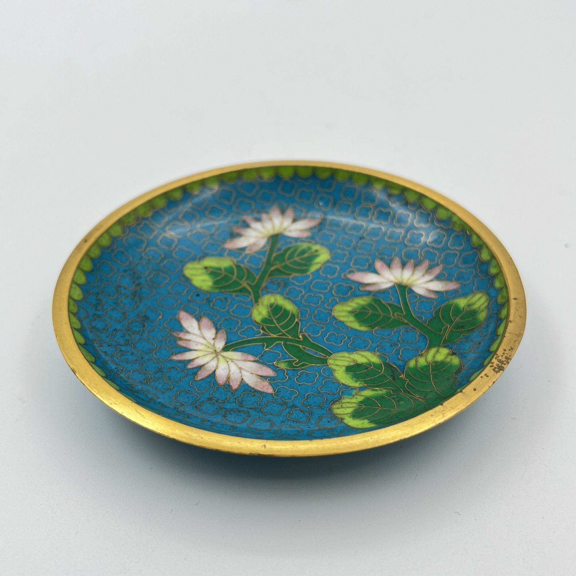 Розетка с цветочным декором на бирюзово-голубом узорчатом фоне с зеленой каймой