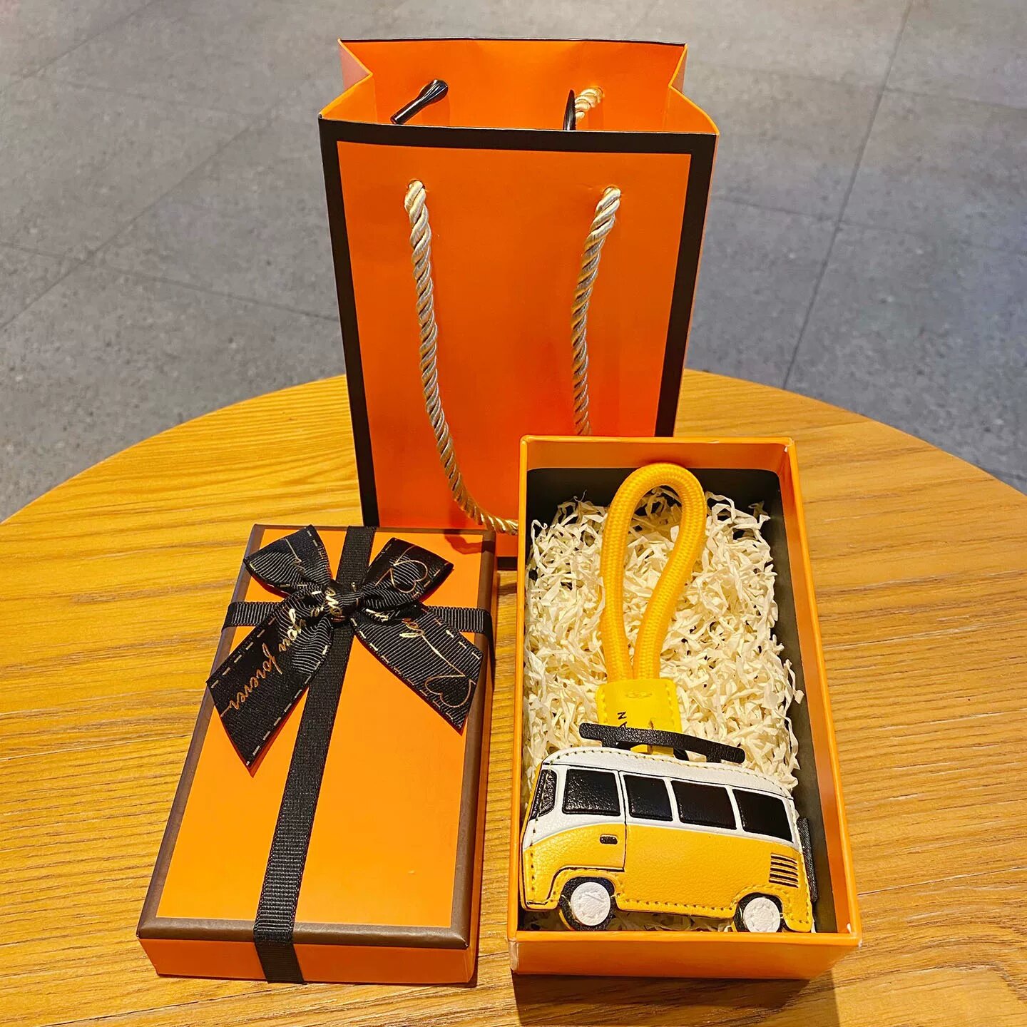 Кожаный брелок в виде автобуса с оранжевой подарочной коробкой и мешком — премиум-ключница
