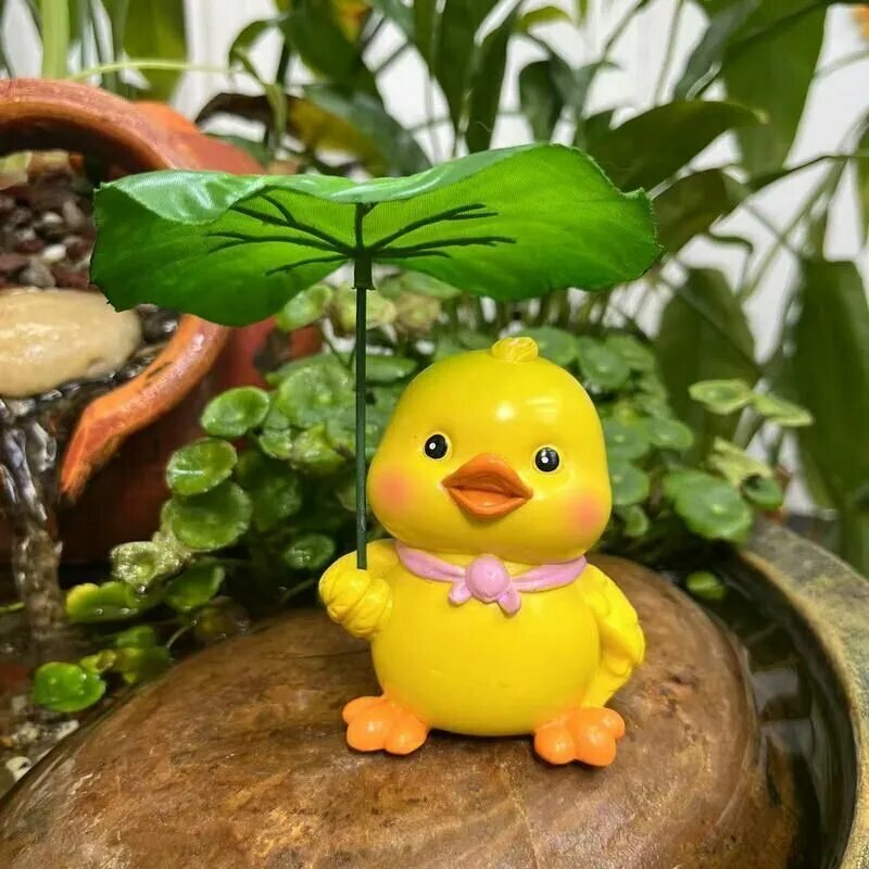 Миниатюрная композиция из листьев лотоса и маленькой желтой уточки, изготовленная из смолы.