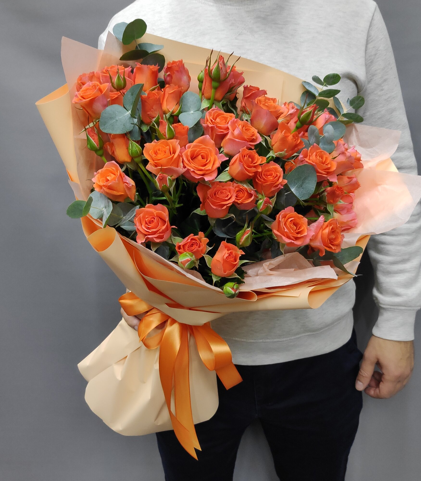 Букет из 11 оранжевых кустовых роз с эвкалиптом высотой 60 см, в коробке с аквабоксом