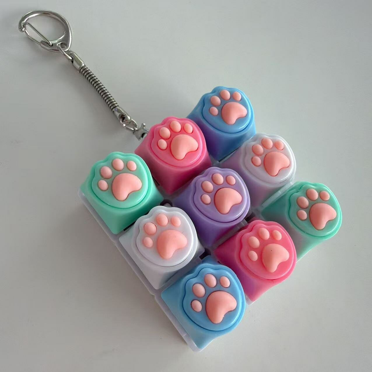 Многоцветная 9-кнопочная антистрессовая силиконовая игрушка-кнопка в виде кошачьей лапки с мультяшным рисунком для тестирования клавиатуры.
