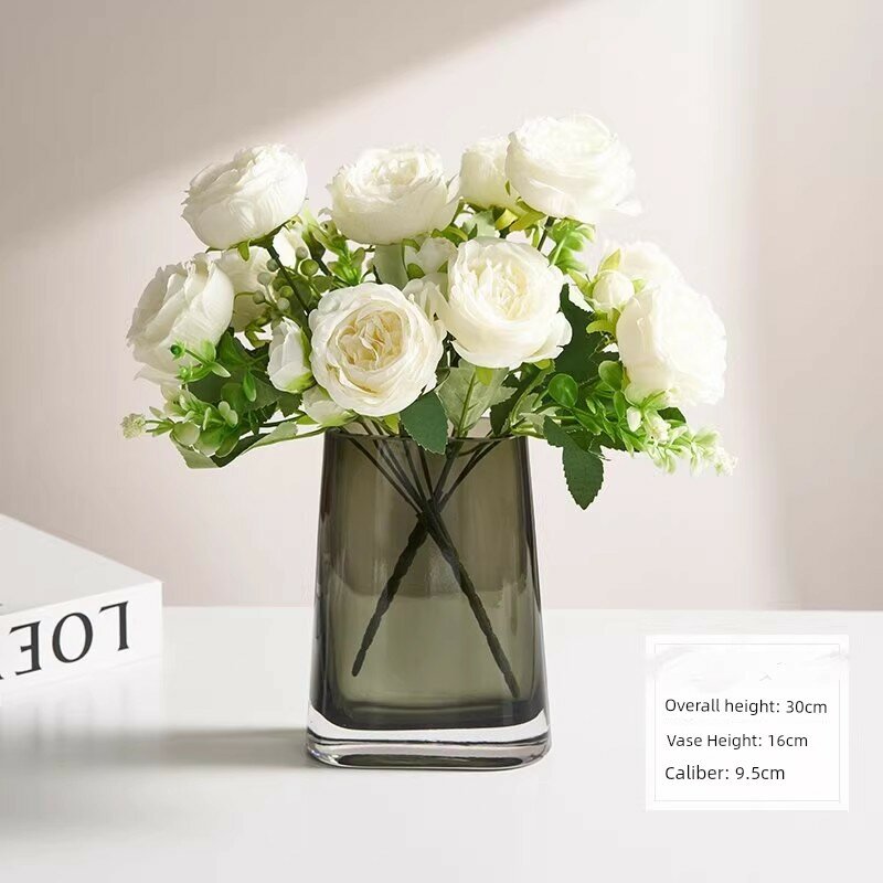 Небольшая стеклянная ваза дымчато-серого цвета с 2 стеблями 5-цветковыми искусственными пионами белого цвета для