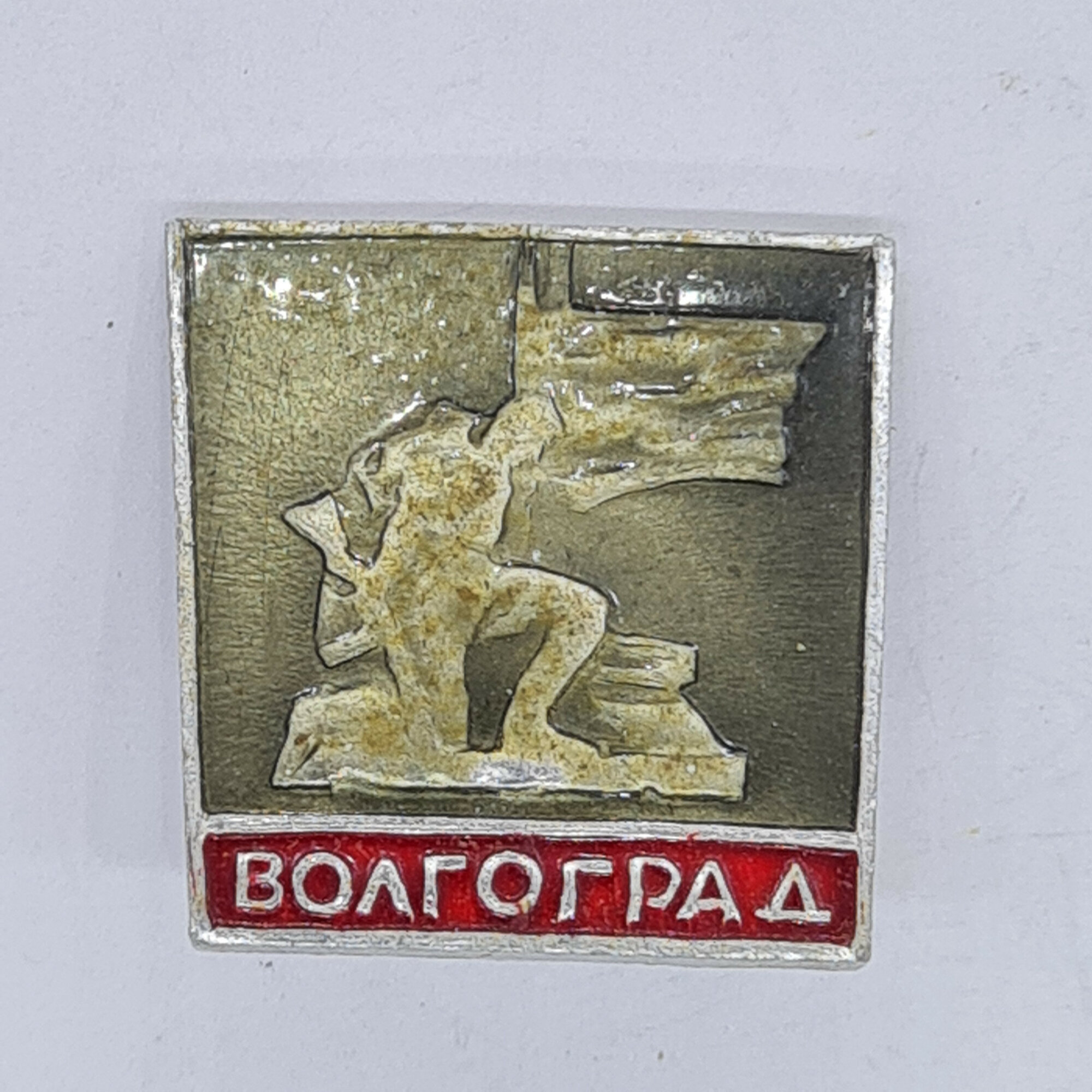 Значок ссср волгоград воин с флагом на пьедестале, фон бронзовый, советский и винтажный