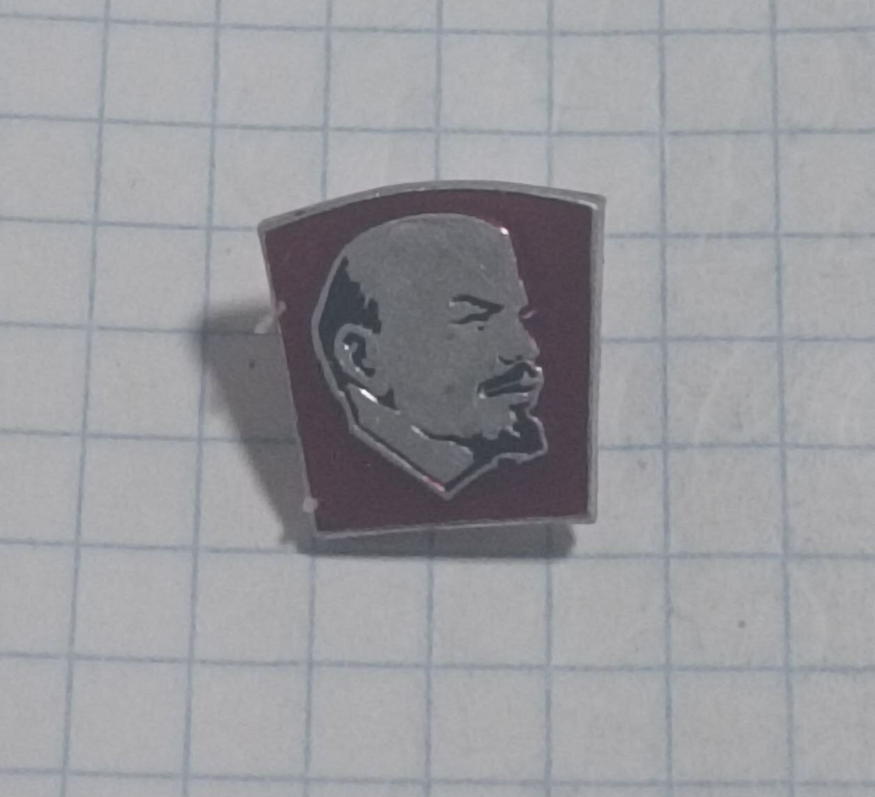Значок с профилем Ленина на бордовом фоне