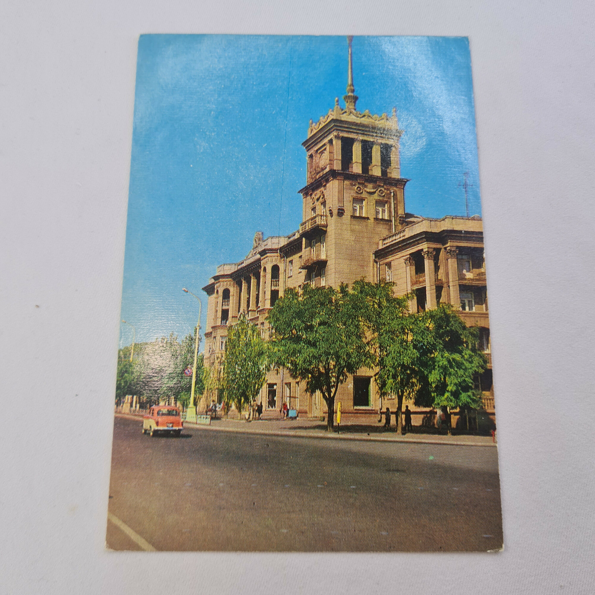 Открытка старинная. Улица Артема, здание 1974 года с деревьями и автомобилями на фоне города.