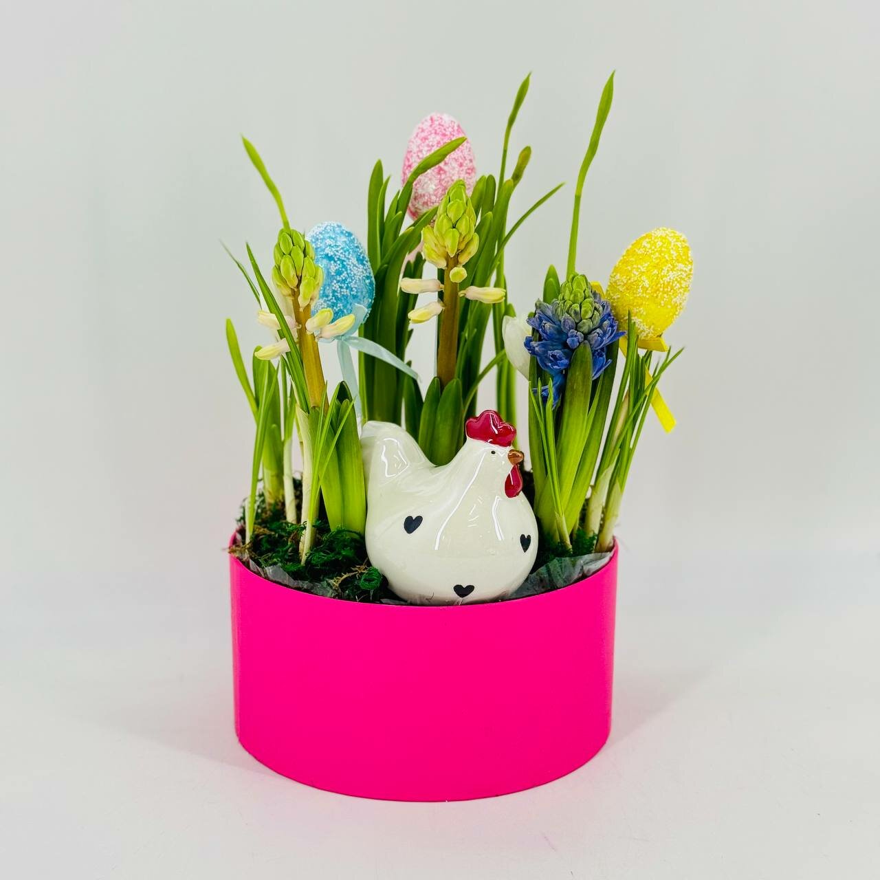 Весенние первоцветы крокусы, гиацинты, нарциссы в шляпной коробке с сувениром курочка