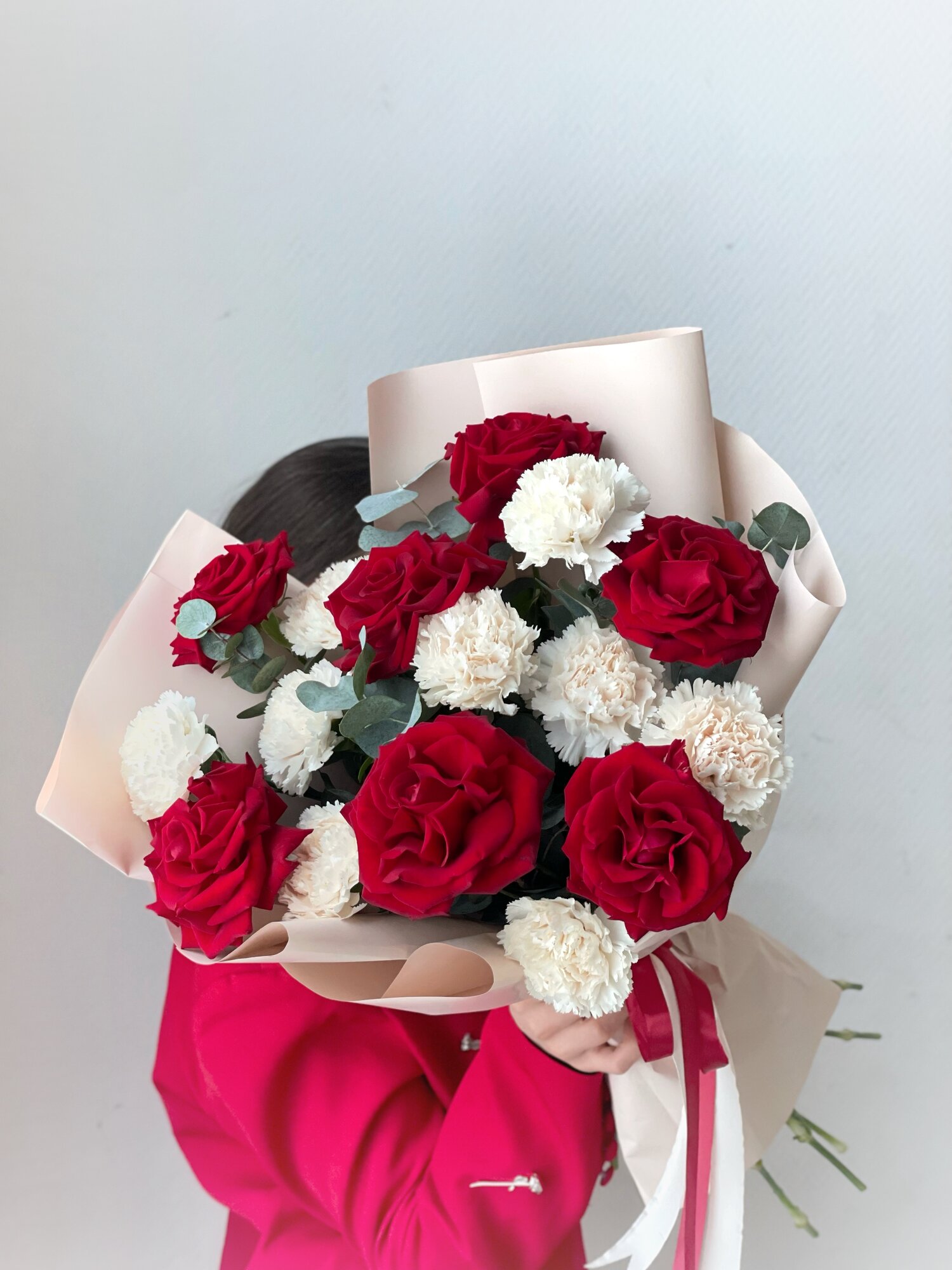 Букет из красных роз, бежевых гвоздик и эвкалипта в стильной упаковке с атласными лентами