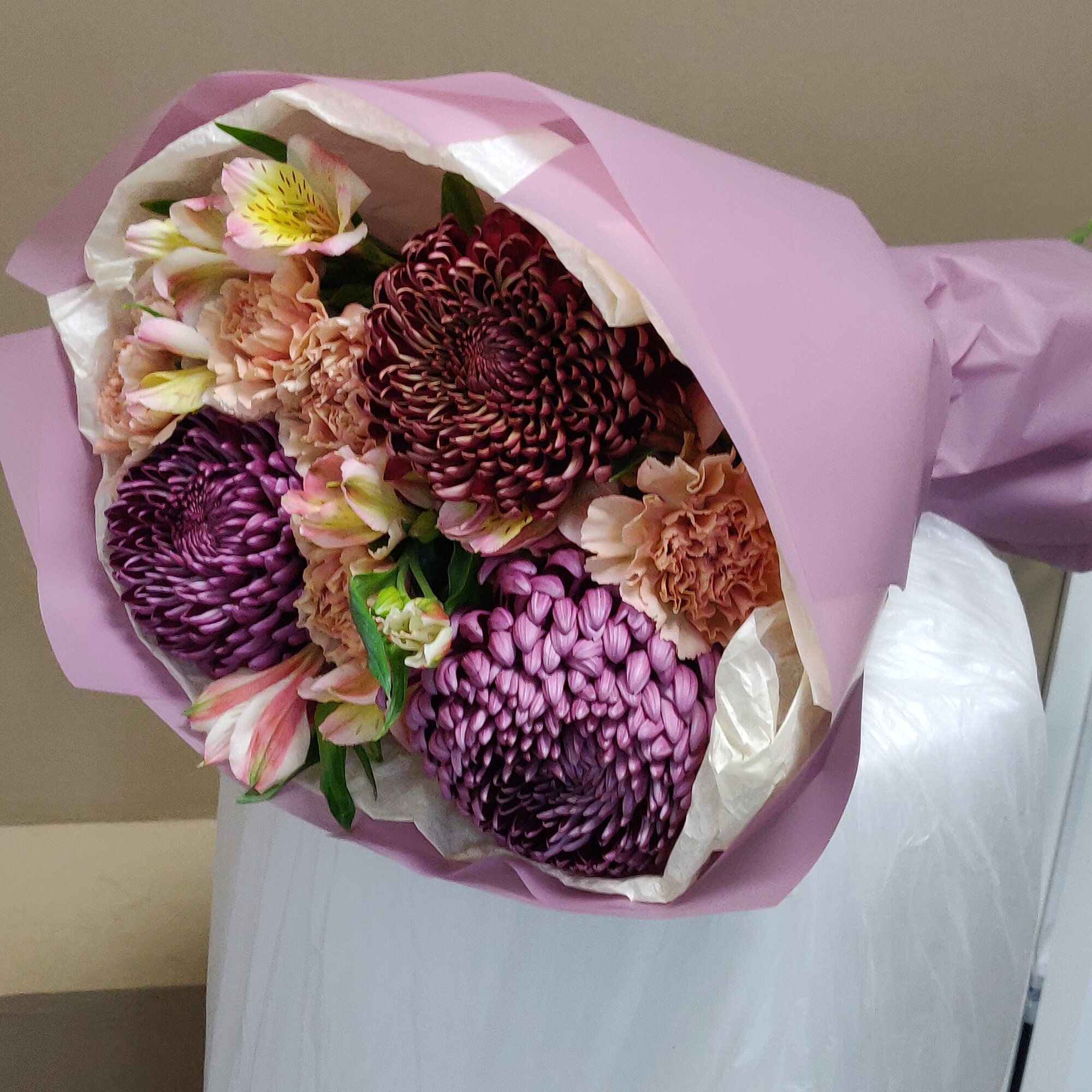 Изысканный букет винных хризантем бигуди, альстромерии и диантусов в эффектной круглой упаковке.