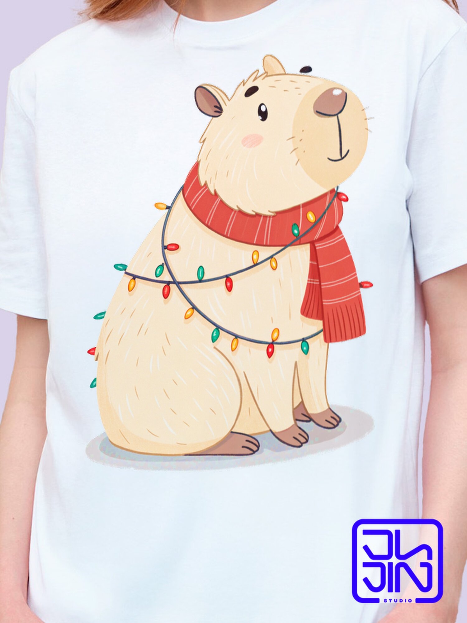 Футболка классическая женская с авторским принтом Веселая молочная капибара в красном шарфе и яркой гирлянде на Рождество, белый хлопковый трикотаж с прикольным рисунком на груди