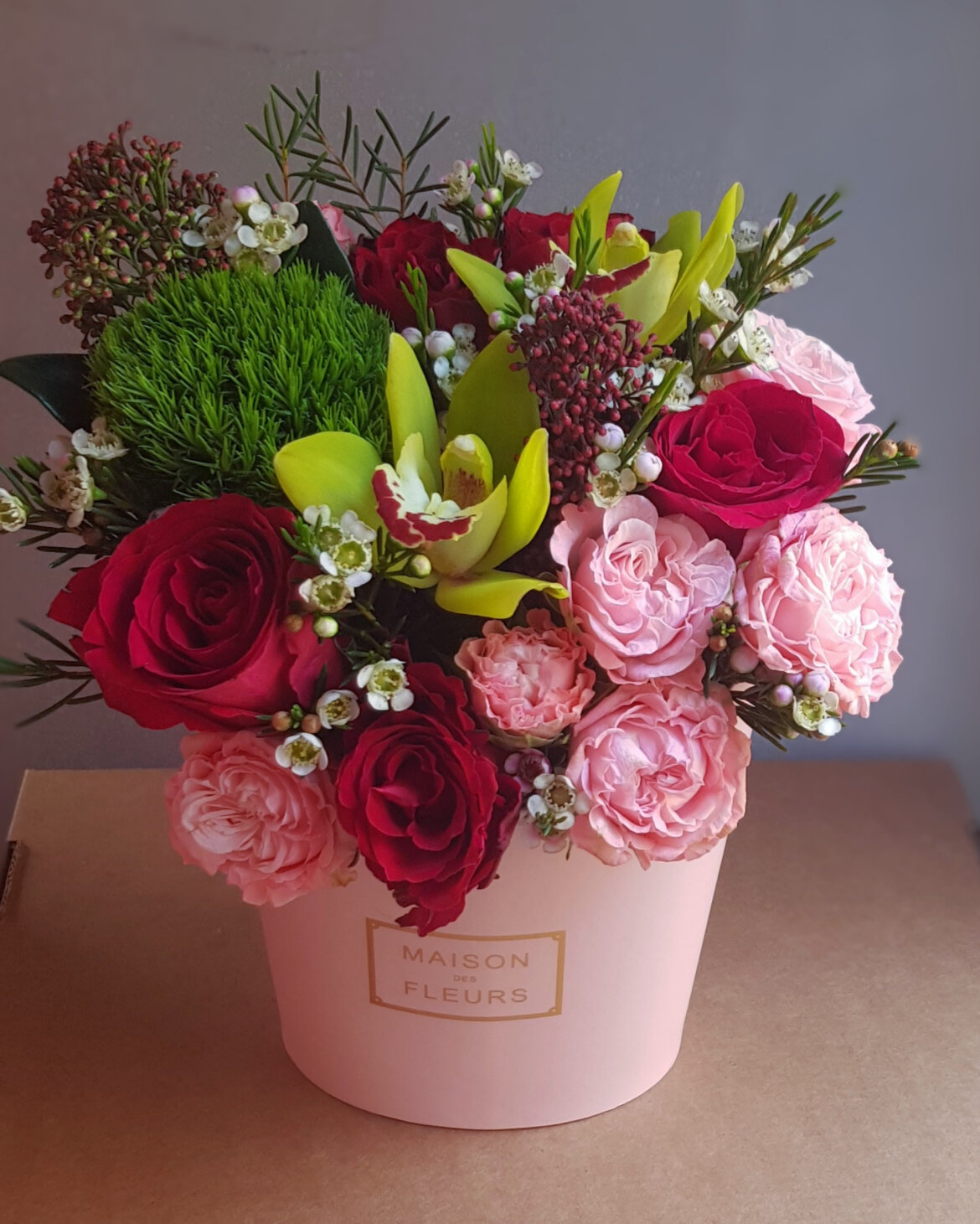 Цветы в розовой коробке. Красная роза, пионовидная роза Бомбастик, зеленая орхидея и зеленый диантус MINI