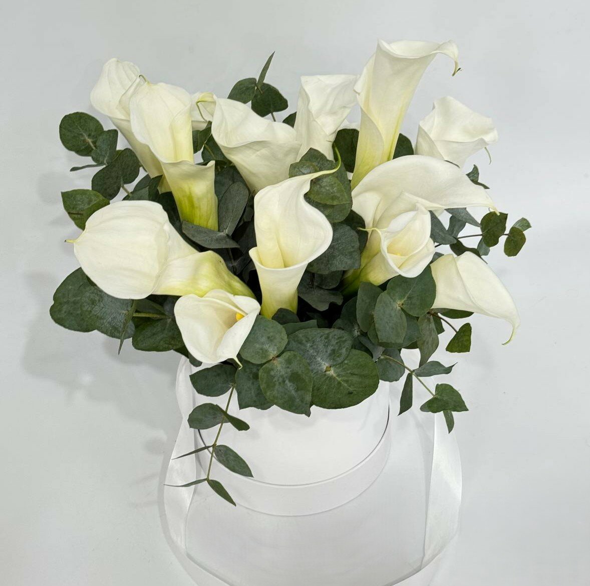 Белые каллы с веточками эвкалипта в шляпной коробке. Цветы живые. Букет из калл